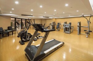 Uma academia com esteiras, elípticos e equipamentos de musculação.