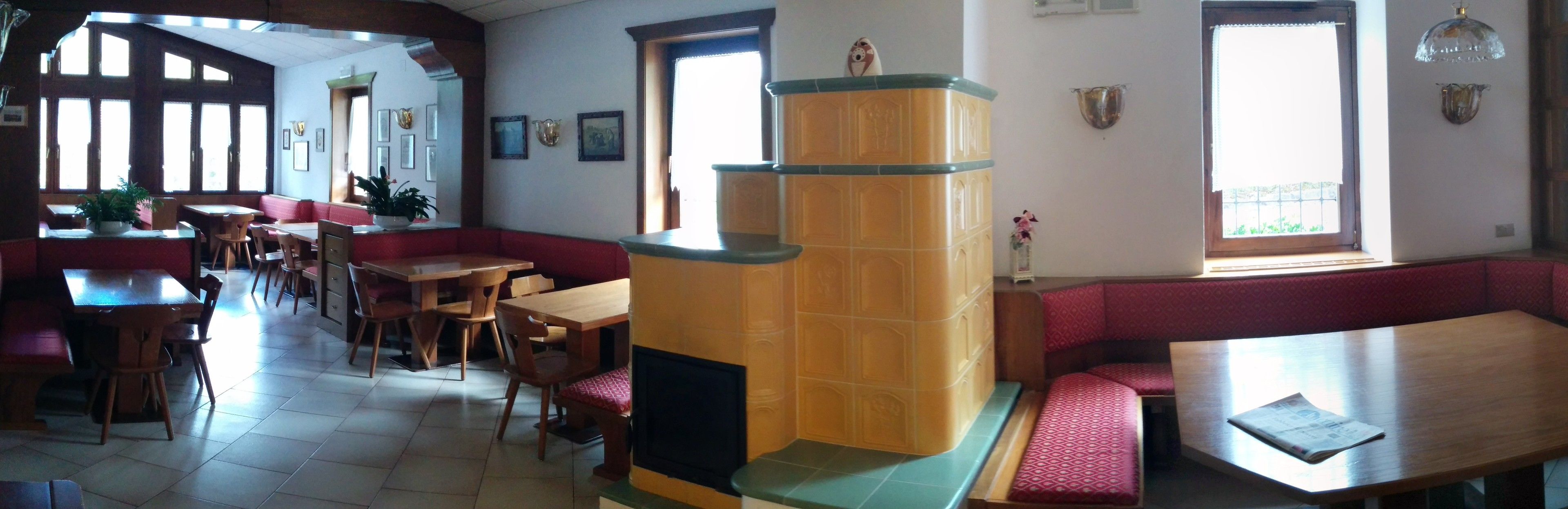 Um restaurante com cabines e mesas, uma lareira e grandes janelas.