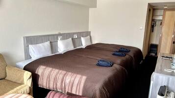 Quarto de hotel com uma cama grande, um sofá, uma mesa com telefone e um guarda-roupa.