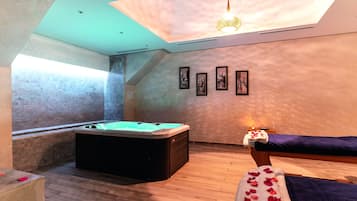 Um quarto de spa com hidromassagem, mesa de massagem e quadros nas paredes.