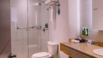 Uma casa de banho moderna com chuveiro em cabine de vidro, sanita e lavatório com espelho.