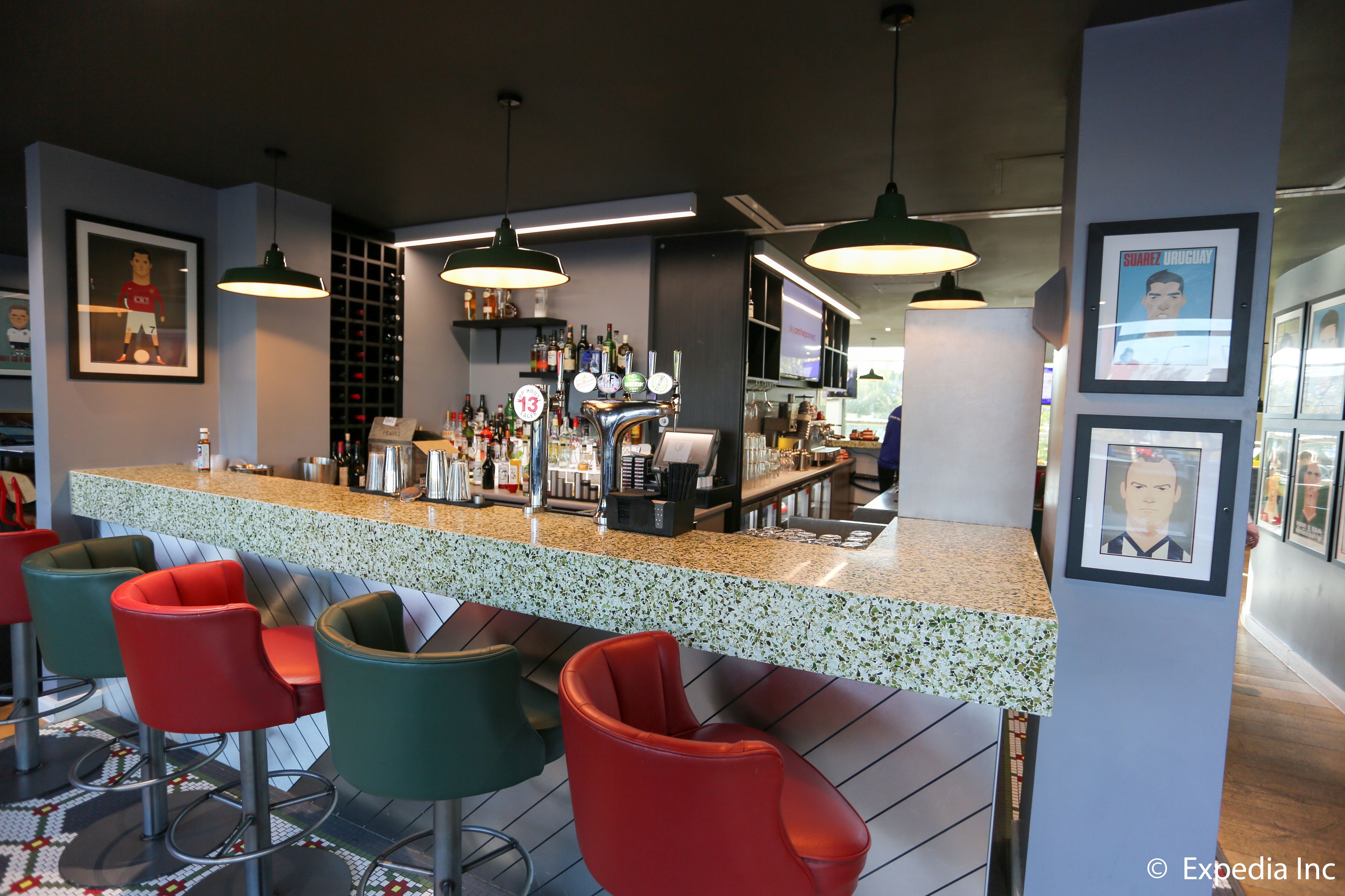 Uma área de bar com balcão, vários bancos e luminárias pendentes.