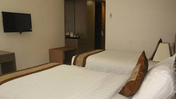 Quarto de hotel com duas camas, uma televisão de tela plana na parede e um espelho sobre as camas.