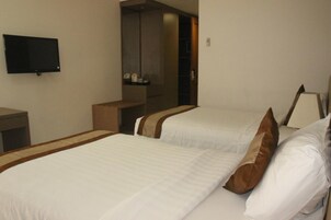 Quarto de hotel com duas camas, uma televisão de tela plana na parede e um espelho sobre as camas.