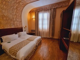 Quarto de hotel com uma cama grande, um guarda-roupa, uma escrivaninha e uma lâmpada.