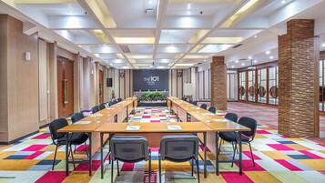 Uma sala de conferência com uma mesa comprida, cadeiras e uma tela exibindo 'THE 101 HOTEL'.