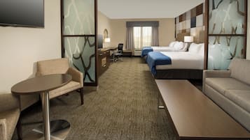 Quarto de hotel com uma cama, duas mesas de cabeceira, escrivaninha, poltrona, sofá e televisão.