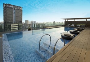 Uma piscina infinita no terraço com espreguiçadeiras e vista para a cidade.