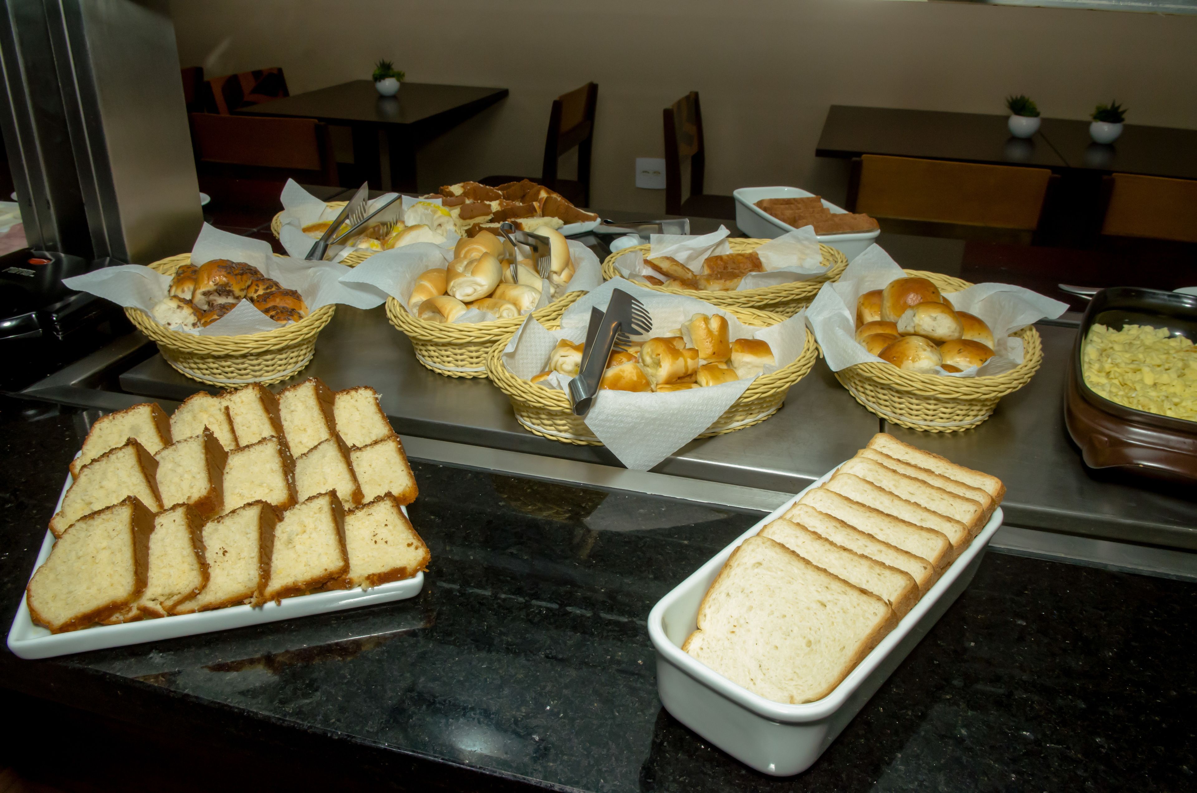 Um buffet com diversos pães e doces em cestas e bandejas.