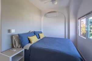 Quarto com uma cama, mesa de cabeceira, ar condicionado e janela.