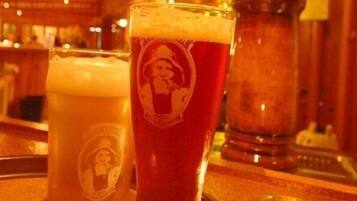 Dois copos de cerveja em um balcão de bar, com uma vela ao fundo.