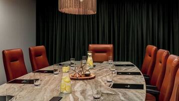 Uma sala de conferências com uma mesa de mármore, cadeiras de couro e um arranjo decorativo.