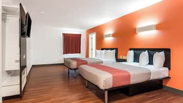 Quarto de hotel com duas camas, um guarda-roupa, uma televisão e uma janela com cortinas.