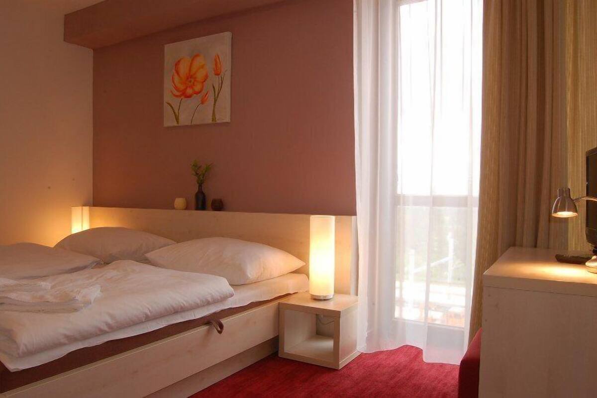 Quarto com cama, mesa de cabeceira, luminária e um quadro na parede.