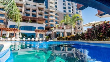 Hotel com piscina, área de estar externa e edifício de vários andares com sacadas.