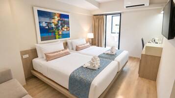 Quarto de hotel com uma cama grande, uma escrivaninha, uma televisão e um quadro na parede.