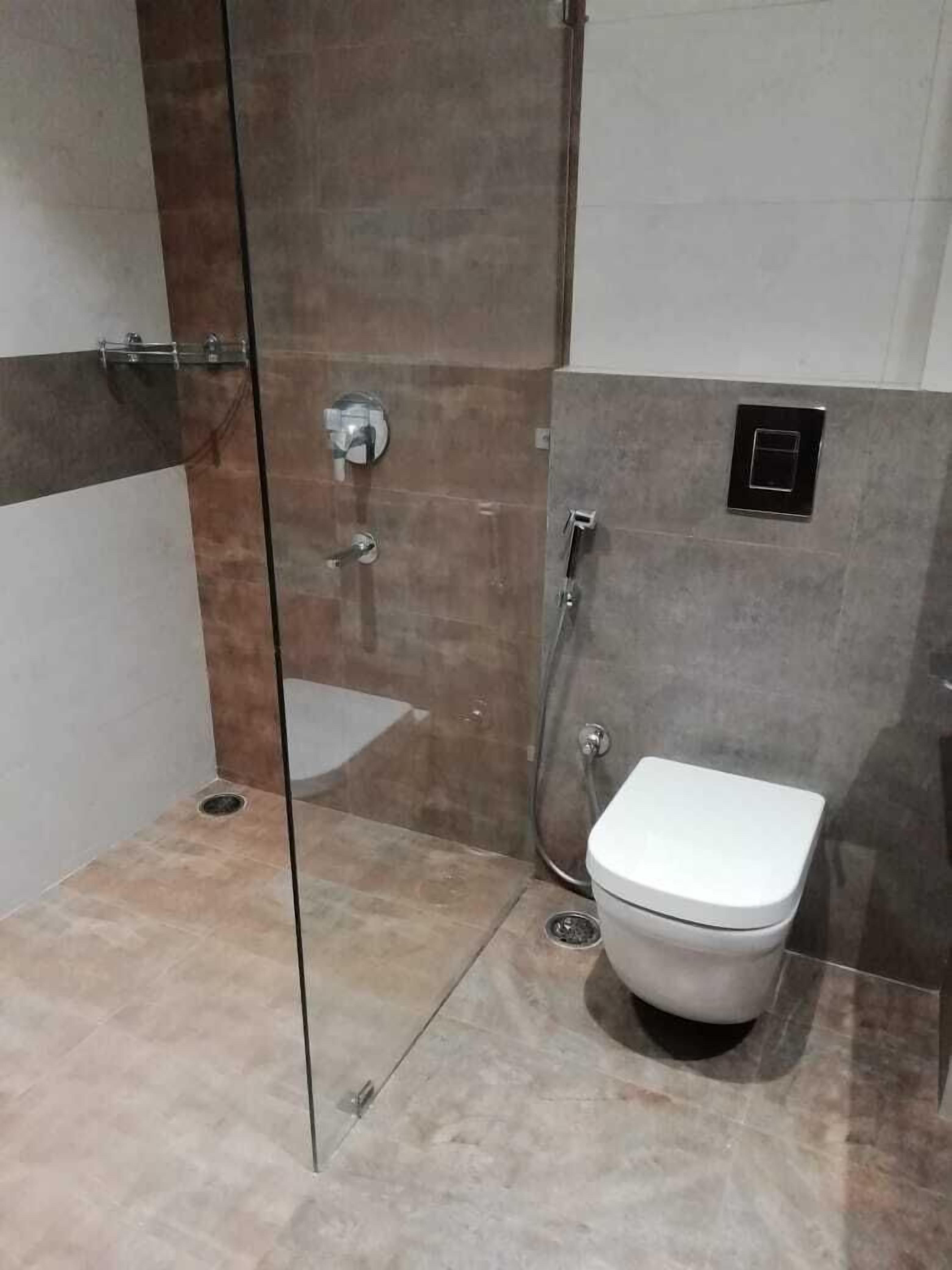 Uma casa de banho moderna com cabine de duche em vidro, sanita branca e lavatório suspenso.
