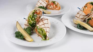 Três wraps em pratos brancos, com fatias de limão e couve.