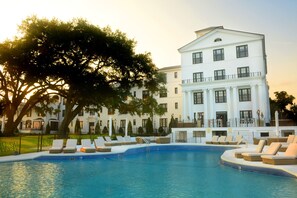 Uma área de piscina com espreguiçadeiras e um edifício grande ao fundo.