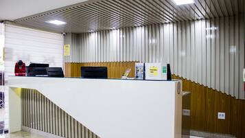 Uma receção com design moderno, parede revestida a madeira e teto inclinado com iluminação linear.
