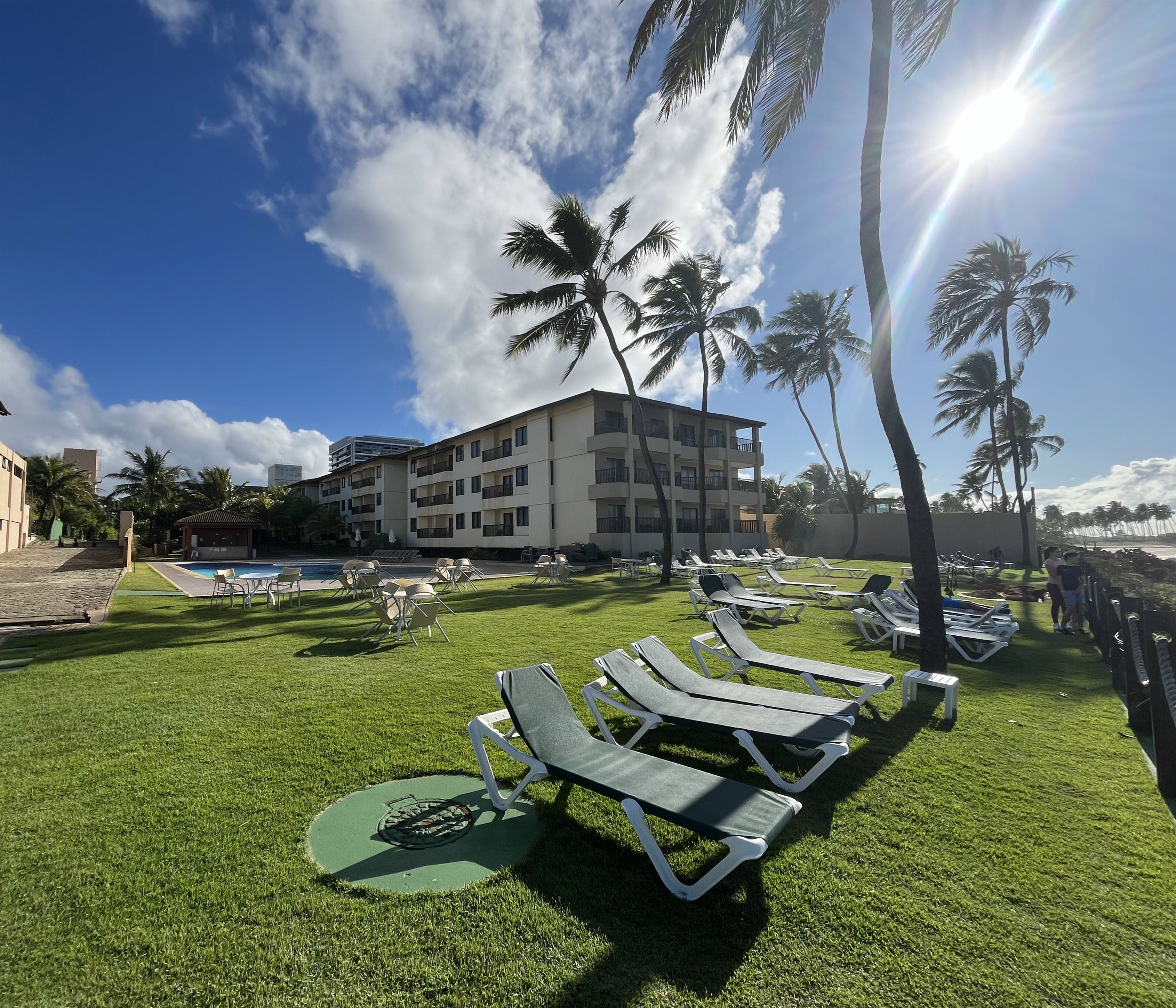 Um hotel com piscina, espreguiçadeiras e palmeiras.