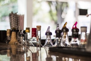 Um bar com diversos garrafas e copos, refletindo na superfície.