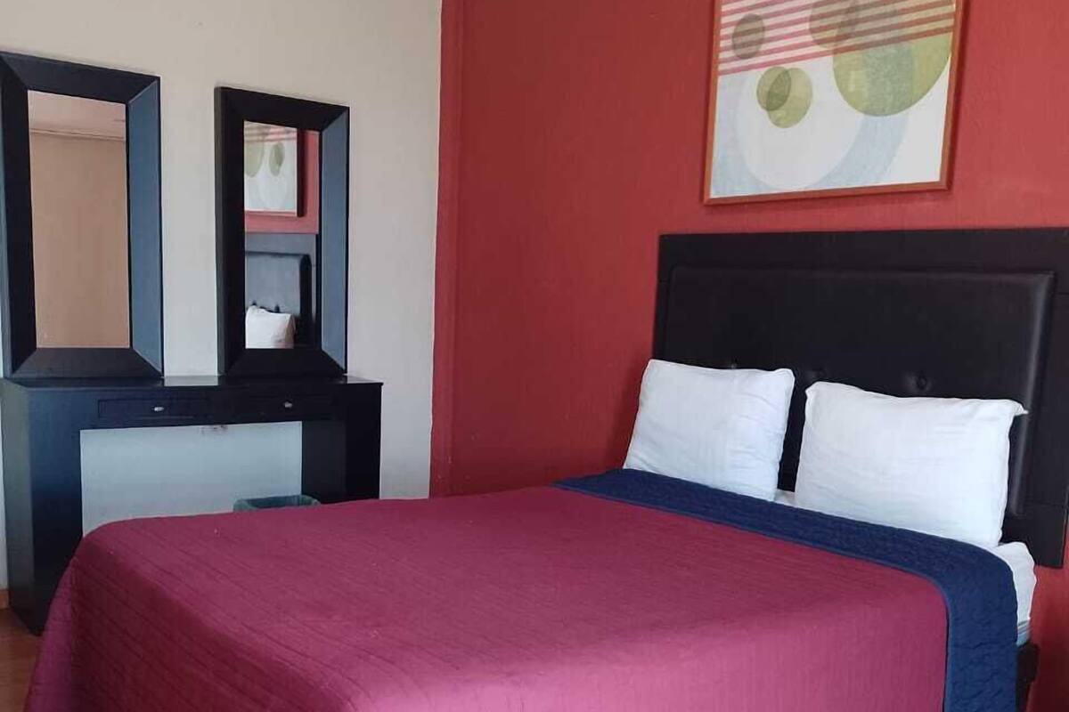 Quarto com uma cama grande, uma cômoda e um espelho.