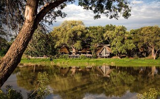 Um imóvel à beira do lago com arquitetura tradicional, um lago e vegetação ao redor.