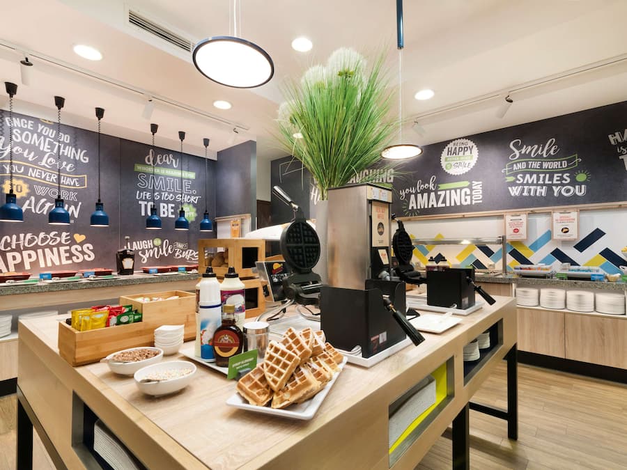 Interior de café com balcão, exposição de waffles e arte inspiradora nas paredes.