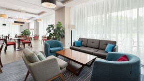 Um hall de hotel moderno com área de estar, janelas amplas e espaço para refeições.