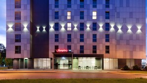 Um hotel moderno com fachada plana, várias janelas e uma entrada destacada com um letreiro de neon.