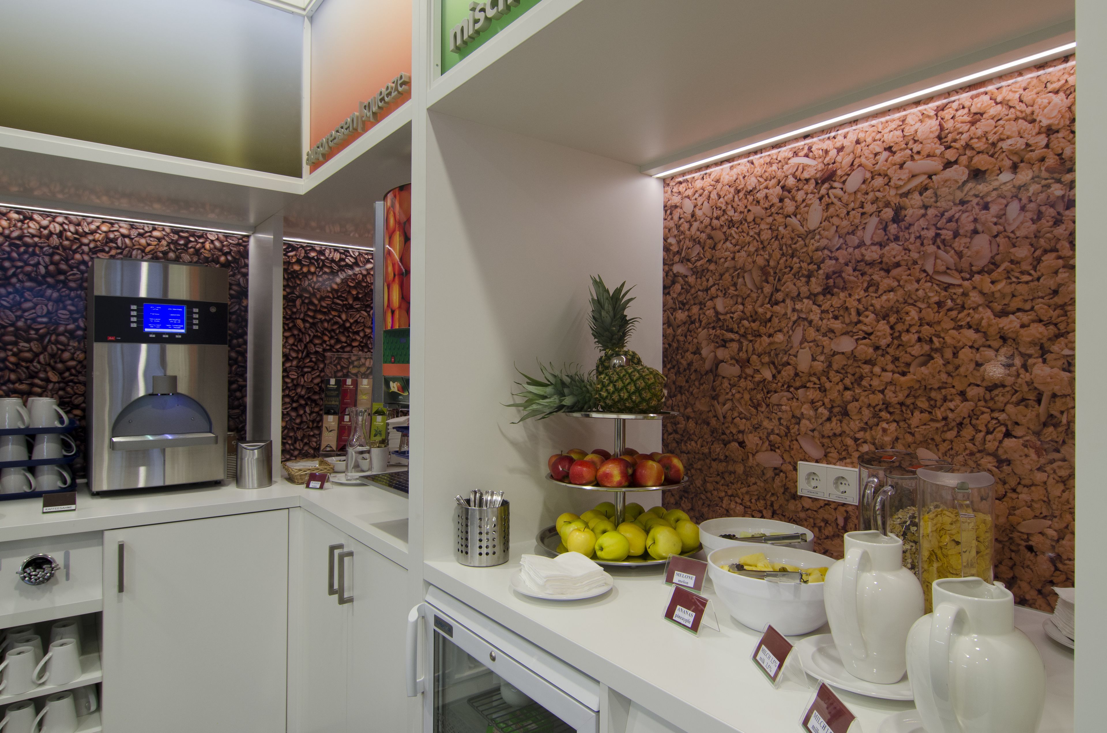 Um buffet de café da manhã com máquina de café, exposição de frutas e diversas opções.