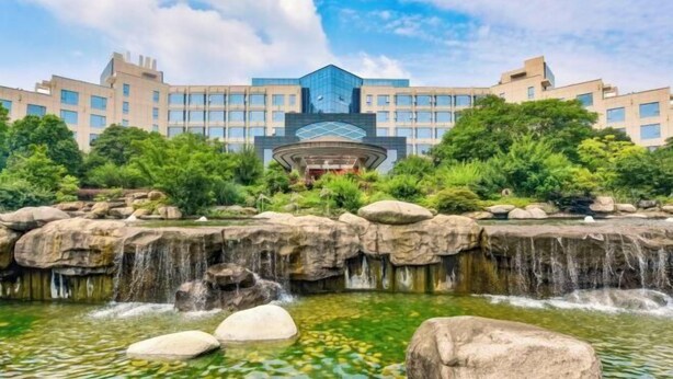 Um hotel com um prédio grande, uma cascata e um lago.
