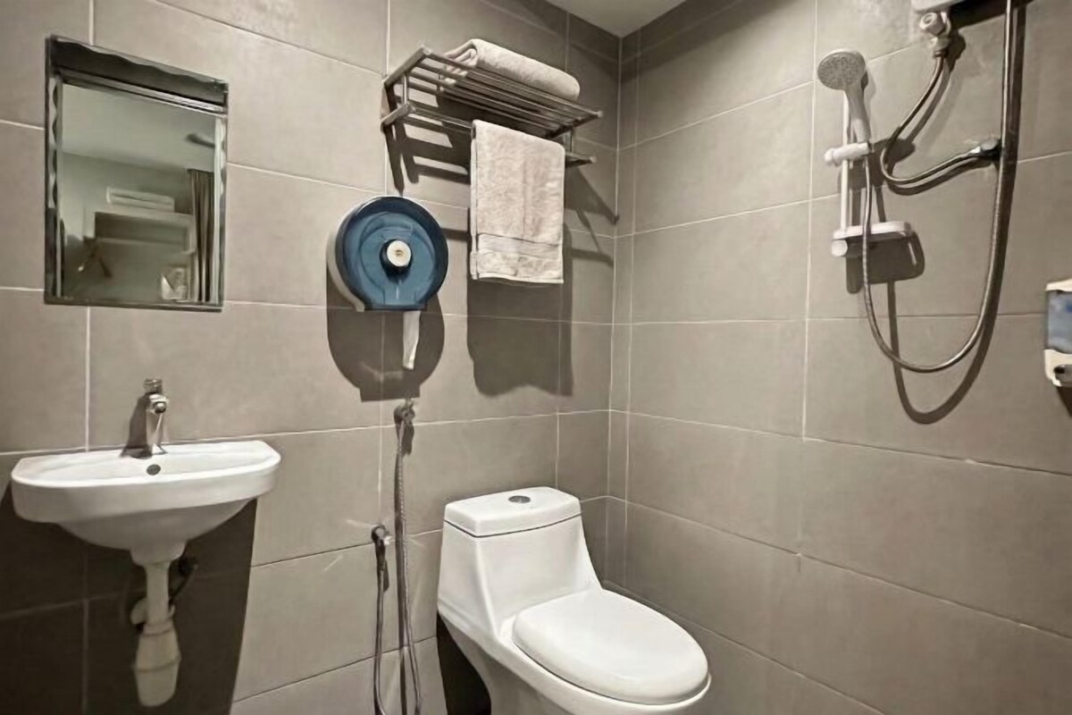 Casa de banho com lavatório, sanita, chuveiro e um porta-toalhas.