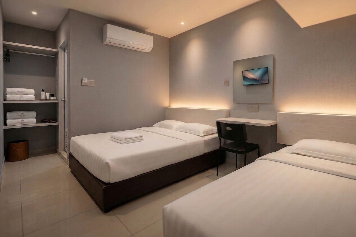 Quarto de hotel moderno com duas camas, uma escrivaninha e uma televisão.