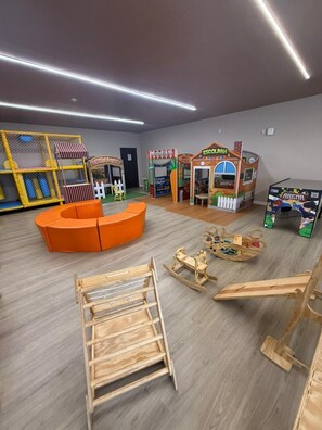 Uma área de recreação com estrutura de escalada, casinha e parquinho de madeira.