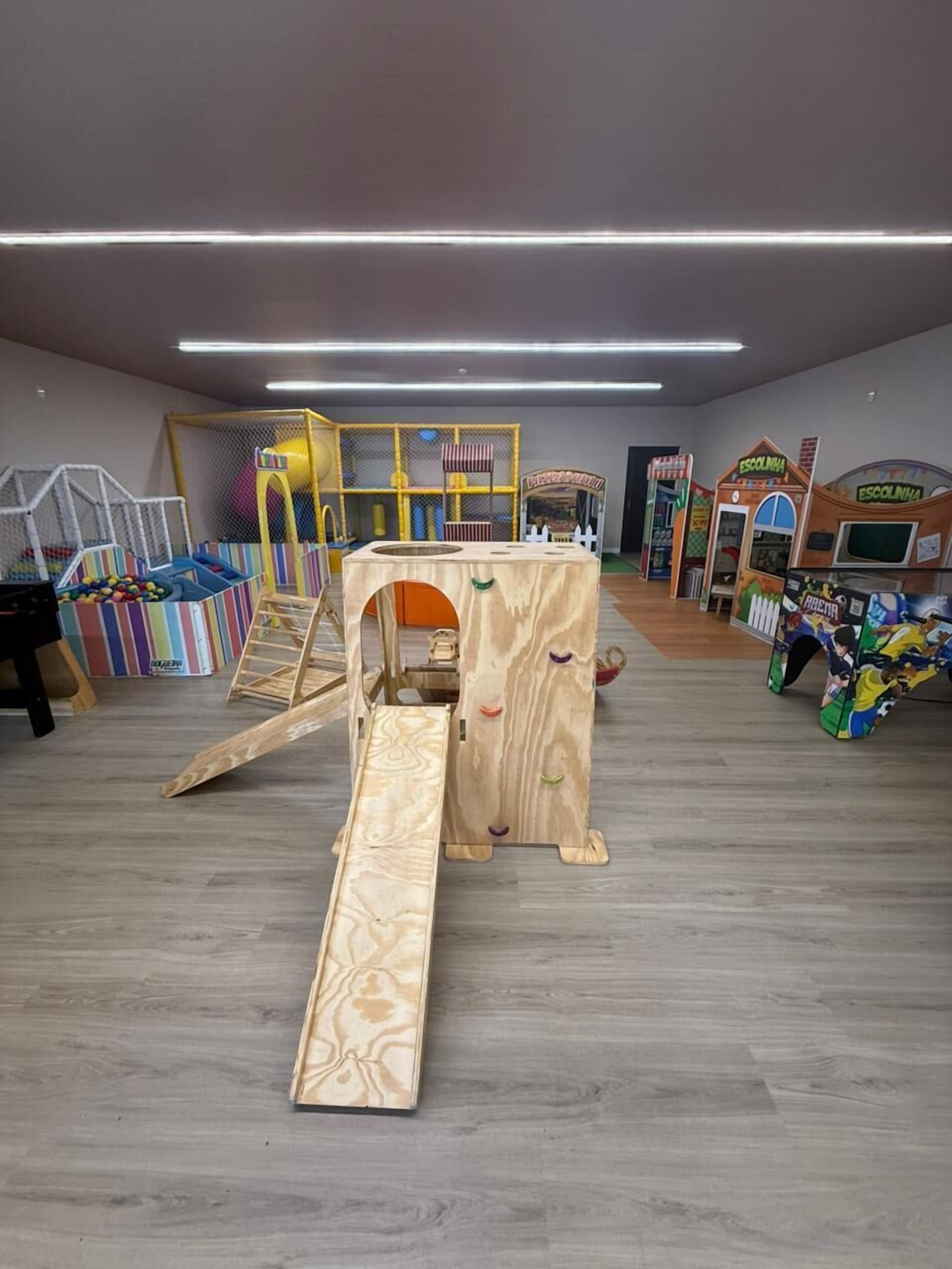 Uma área de recreação com escorrega, estruturas de escalada e equipamentos coloridos.