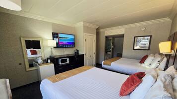 Quarto de hotel com duas camas, televisão, secretária com micro-ondas e espelho.
