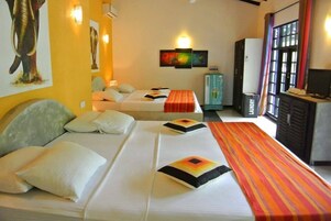 Quarto de hotel com duas camas, um guarda-roupa, televisão e obras de arte nas paredes.