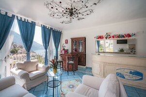Sala de estar com vista para o mar, um armário de madeira e um espaço bar com bandeiras.