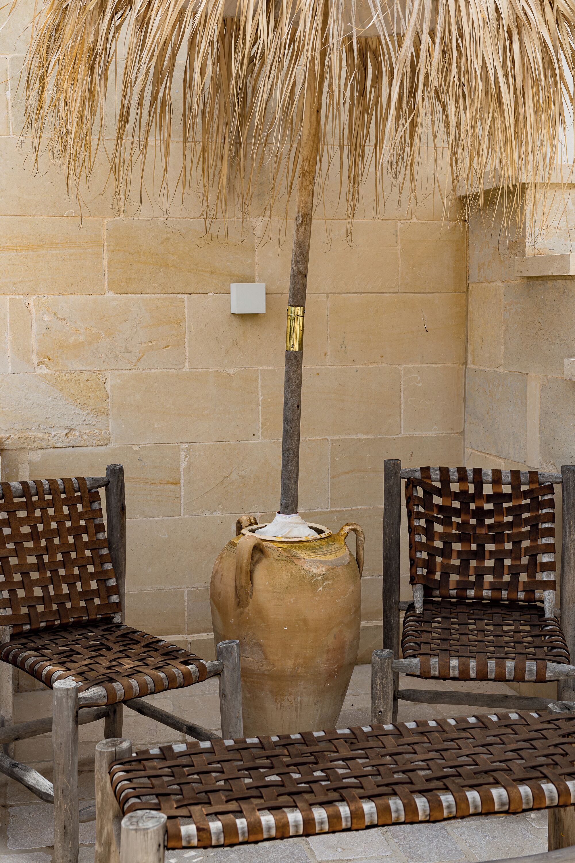 Uma área de estar com cadeiras de fibra natural e um vaso grande.