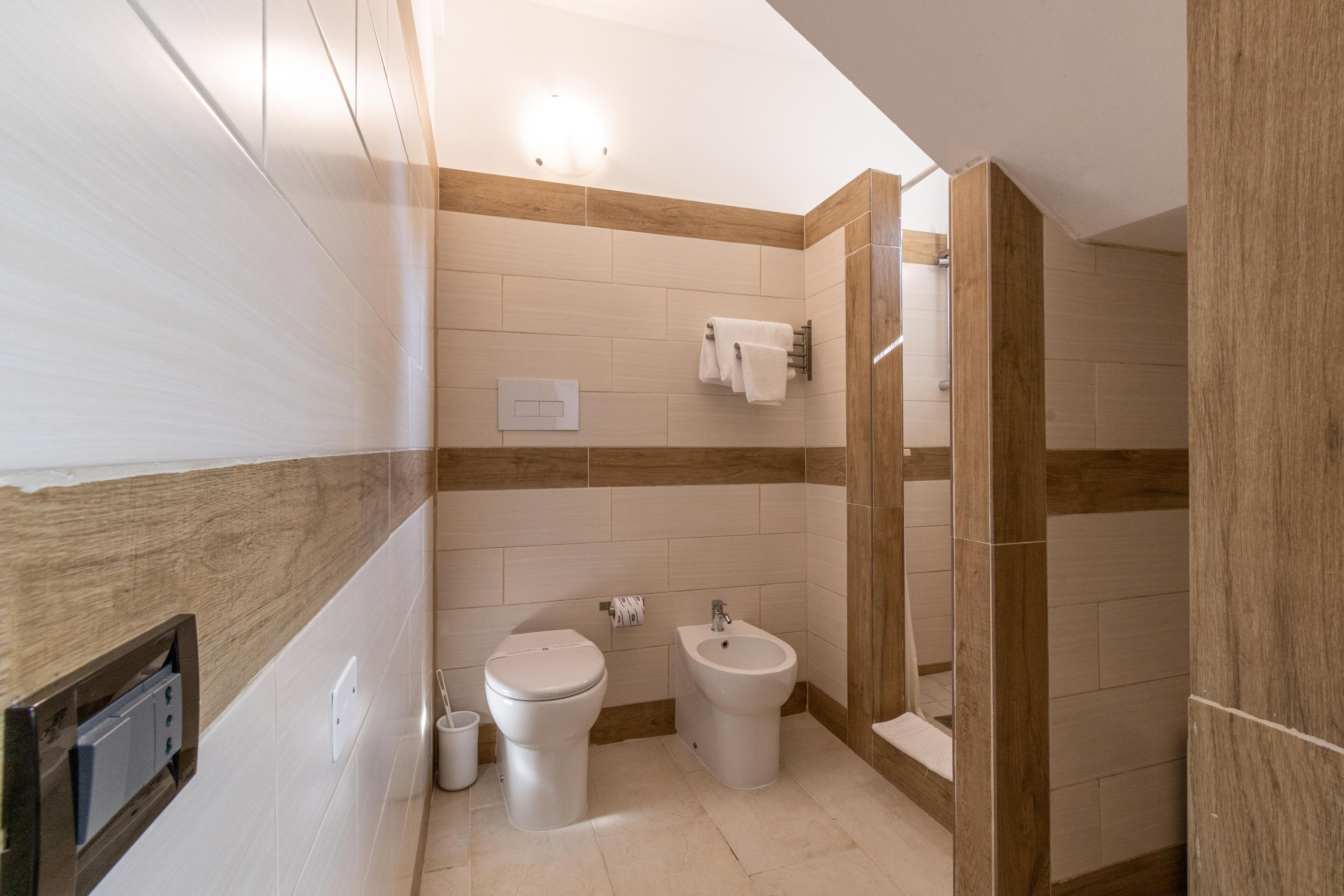 Casa de banho moderna com sanita, bidé e zona de duche.