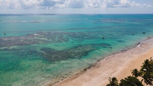Uma praia com águas turquesa cristalinas, areia dourada e palmeiras.