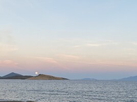 Mar calmo com montanha distante e lua brilhante.