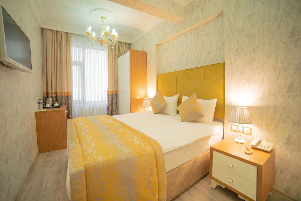 Quarto de hotel com uma cama grande, abajures, mesa de cabeceira, televisão e guarda-roupa.