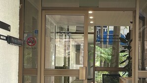 Entrada de hotel com porta de vidro, placa de proibido fumar e aviso com horário de expediente.