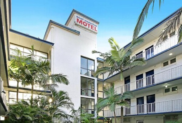 Um motel de vários andares com uma placa que diz 'Boat Harbor Motel'.