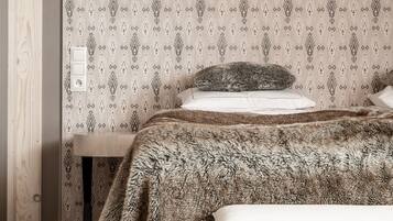 Quarto com cabeceira estampada, mesa de cabeceira, luminária, obra de arte abstrata grande, tapete estampado e um banco com design exclusivo.