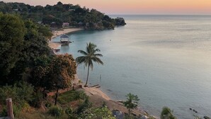 Vista costeira com uma praia, um gazebo e uma fileira de casas à beira-mar.