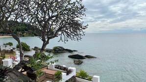 Um resort costeiro com vista para o mar, um caminho arborizado e áreas de estar ao ar livre.